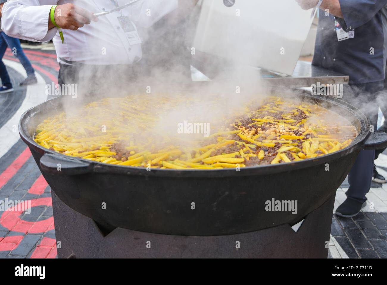 food festival. The cook prepares pilaf in a large cauldron. Stirring ...