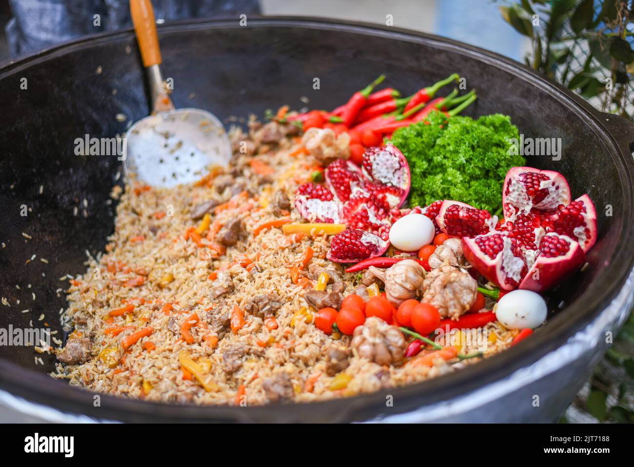 food festival. The cook prepares pilaf in a large cauldron. Stirring ...
