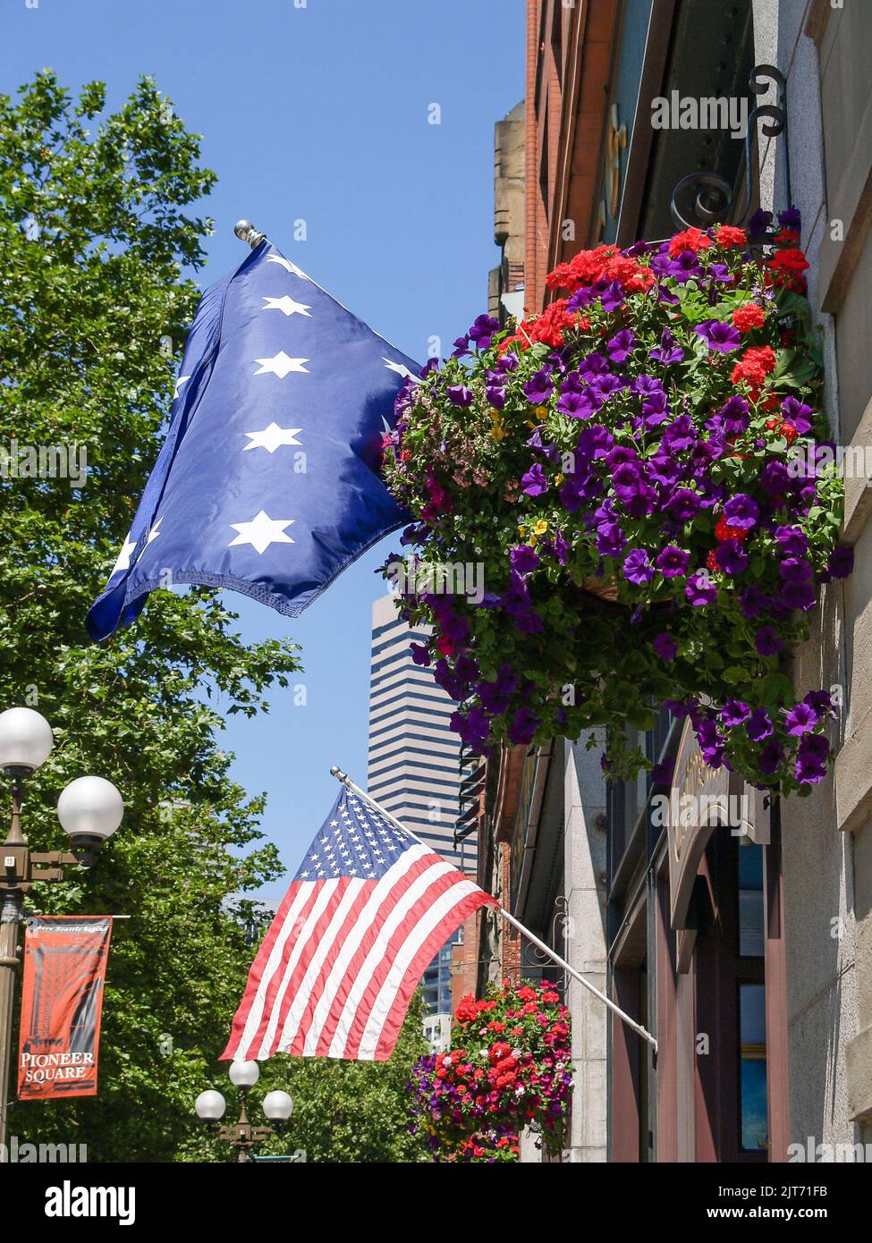 America flags and hanging flower baskets on side of building in Pioneer ...