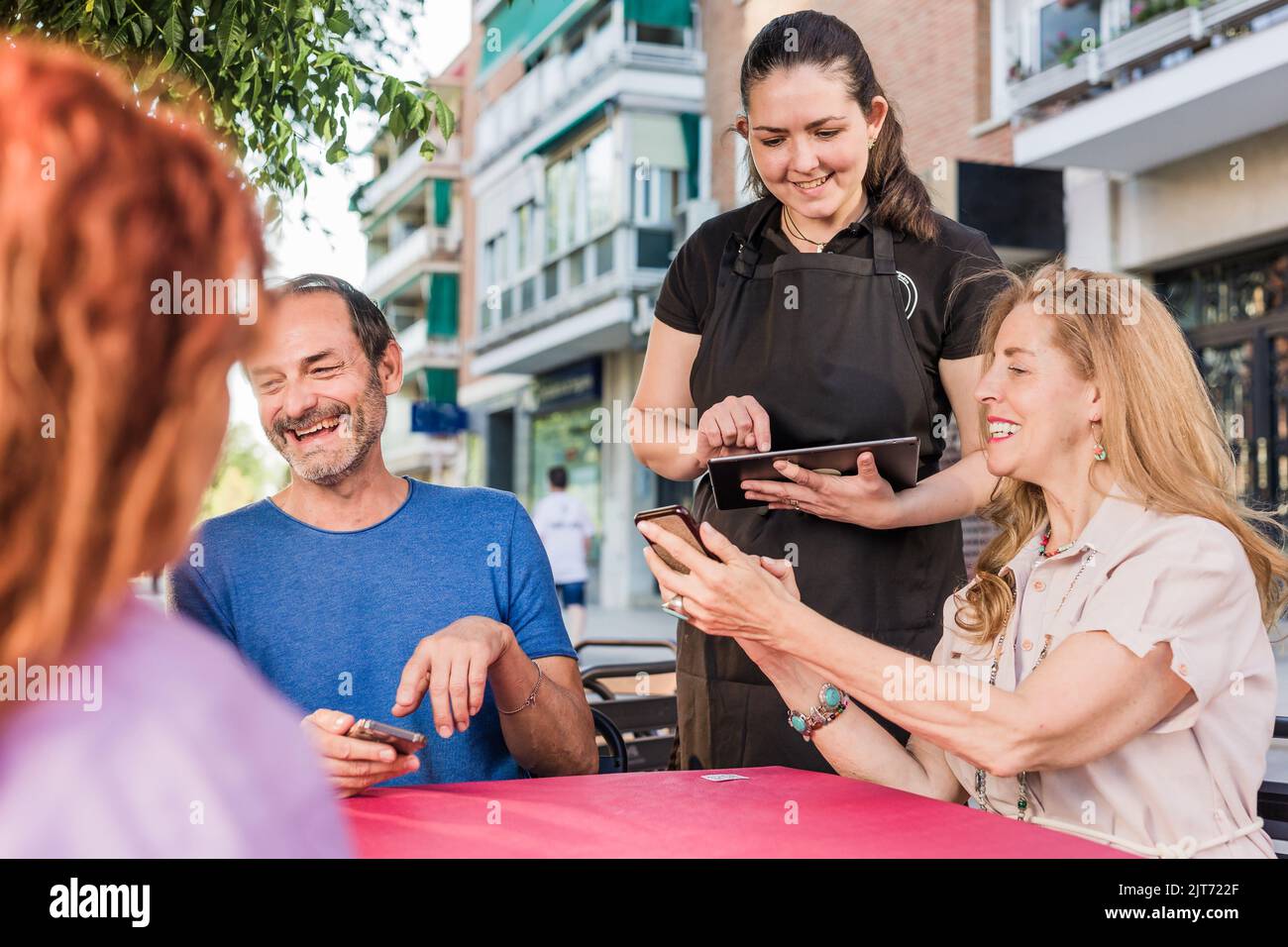 mature group order food in restaurant. waitress using smartphone and ...