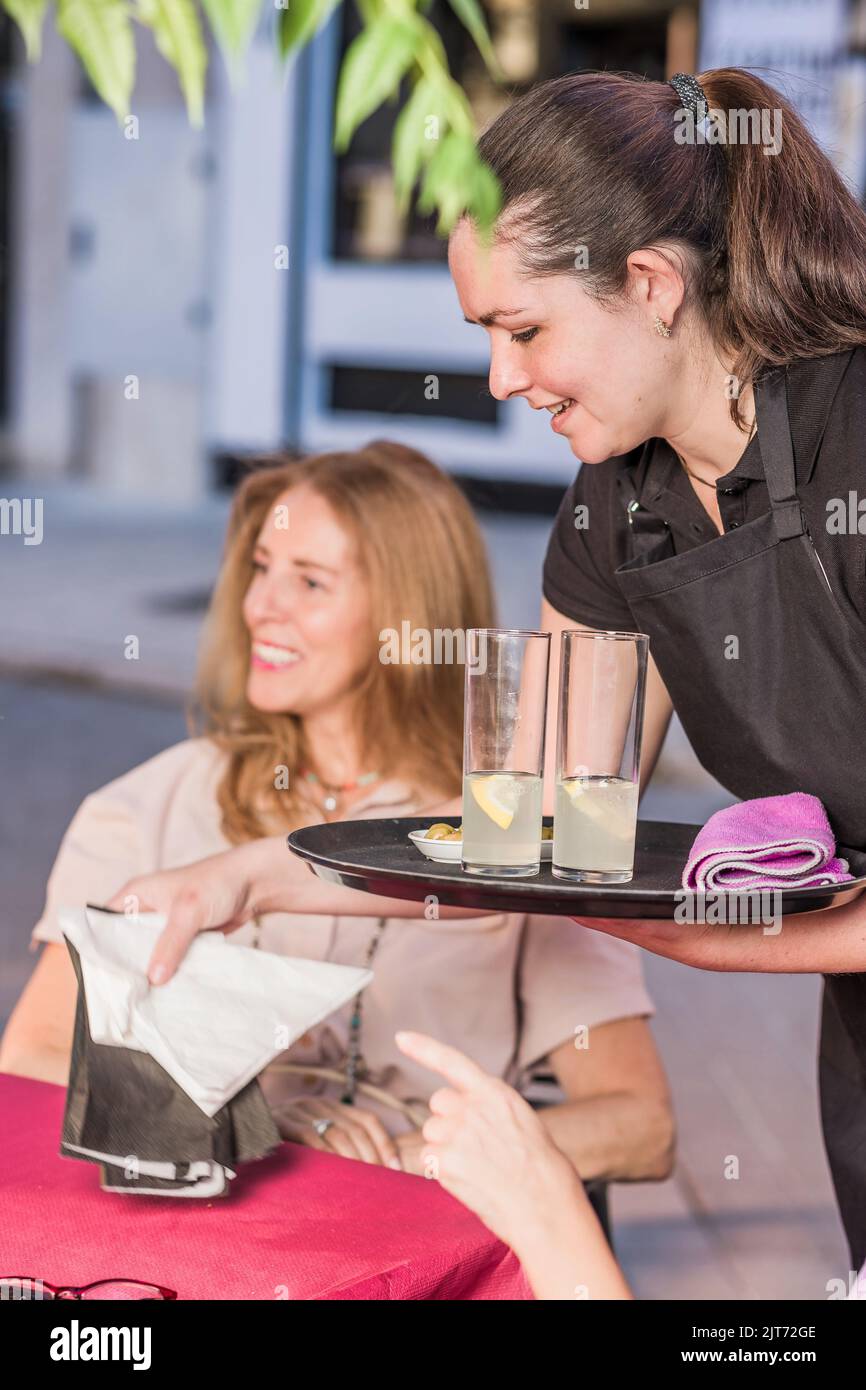 latin waitress woman smiling serving food in restaurant to a mature ...