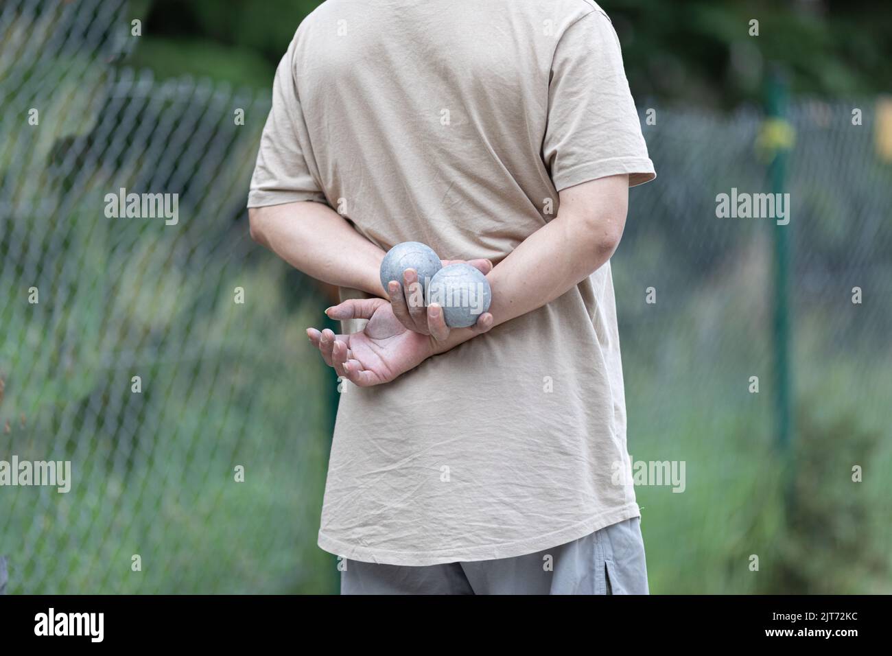 A Petanque player holds the balls behind his back Stock Photo - Alamy