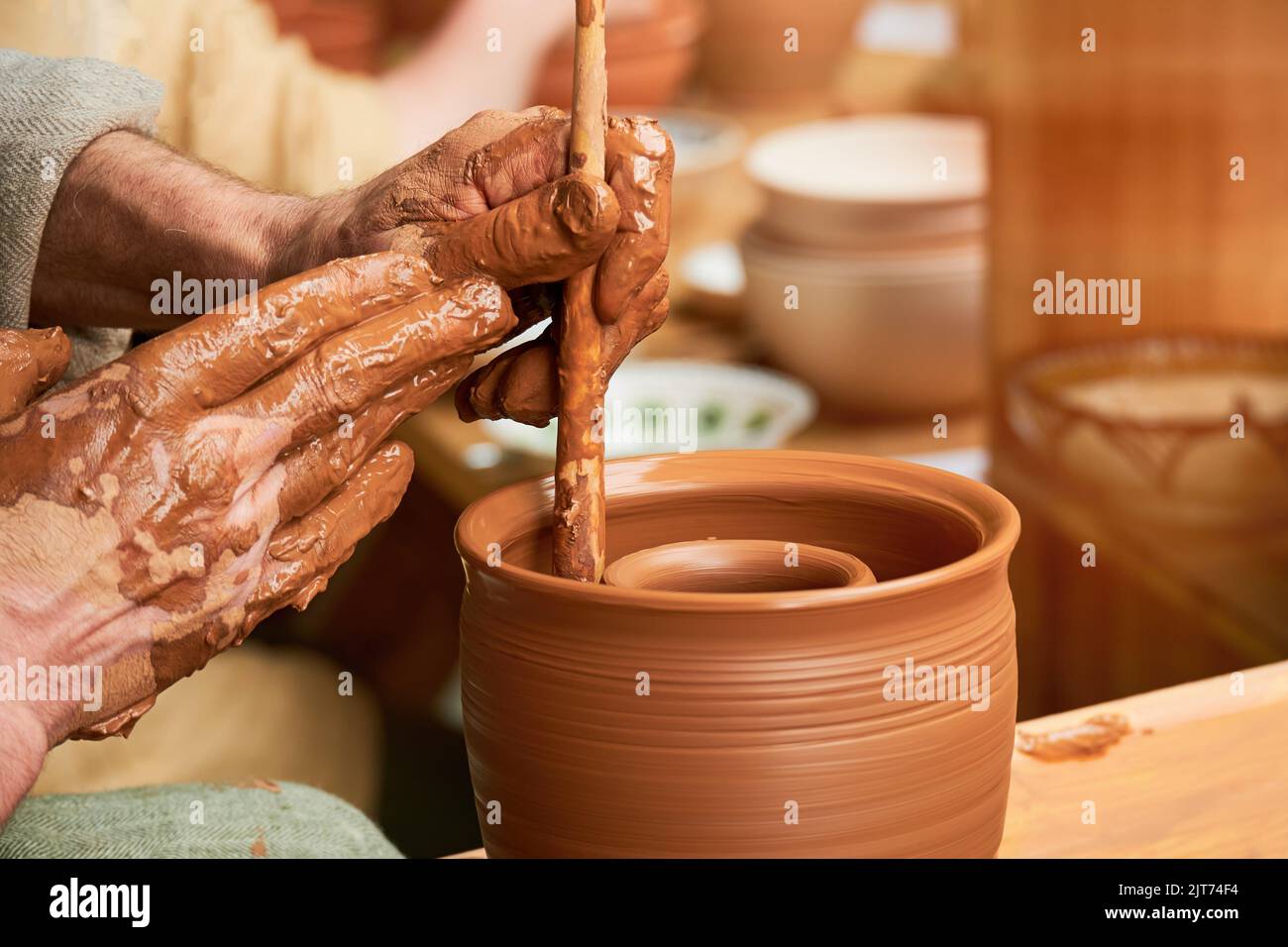 A man in old medieval Byzantine clothes sits behind a vintage potter's ...
