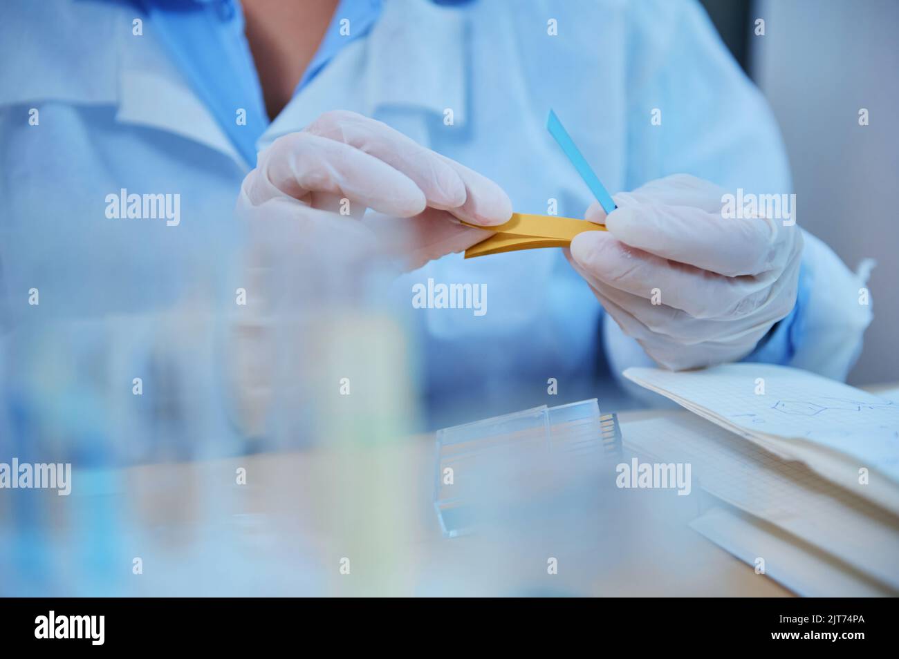 Details: Hands of scientist hold a PH indicator strip for measuring the ...