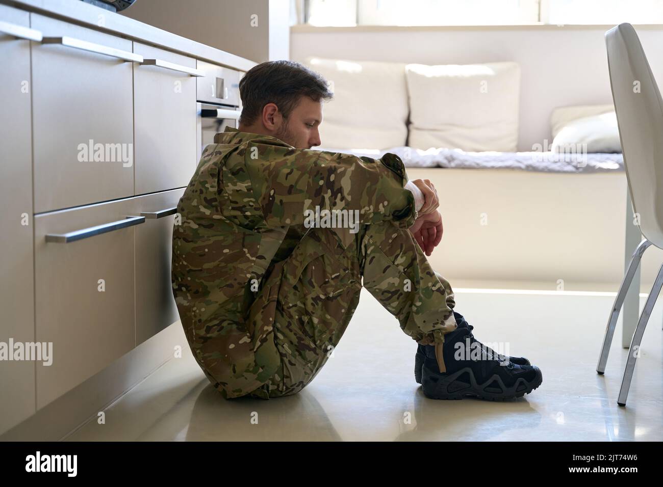Upset soldier sits on the floor hugging his knees Stock Photo - Alamy