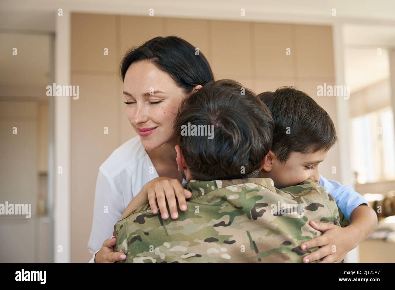 Man in military uniform hugs a woman and a child Stock Photo - Alamy