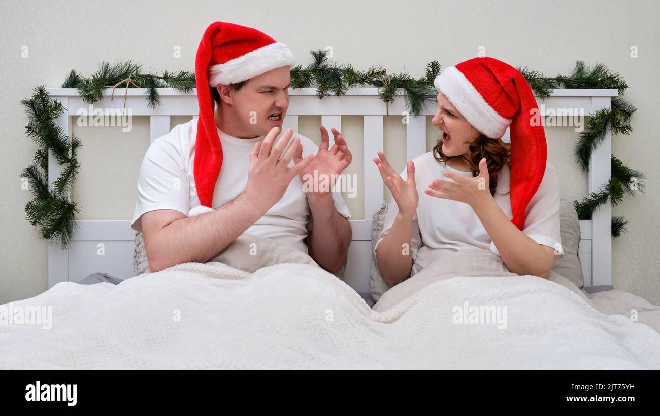 A woman and a man quarrel on a bed decorated for Christmas on New Year ...