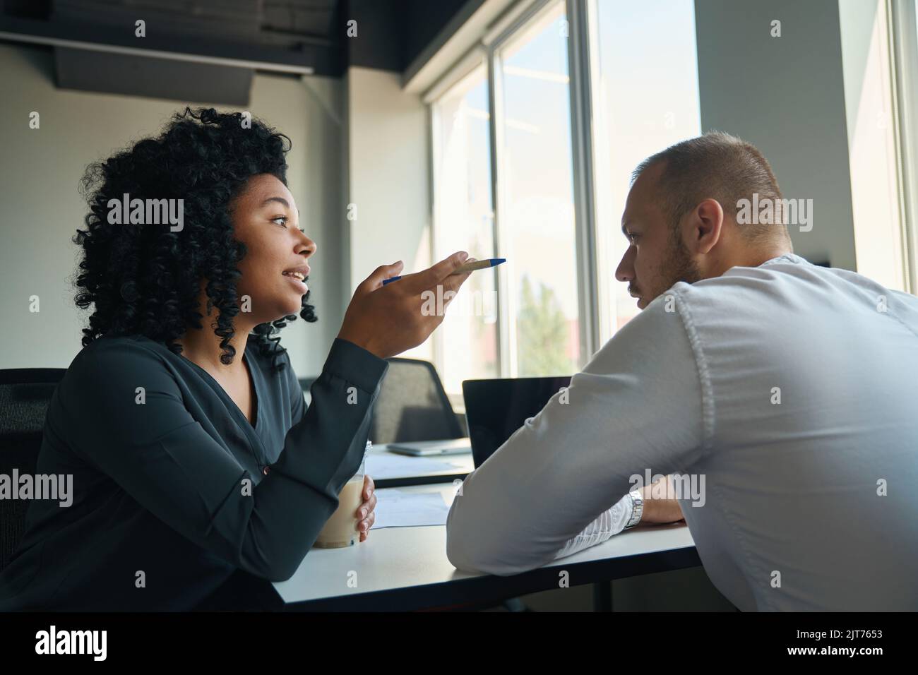 Employees chatting at a desk in a simple bright office Stock Photo - Alamy