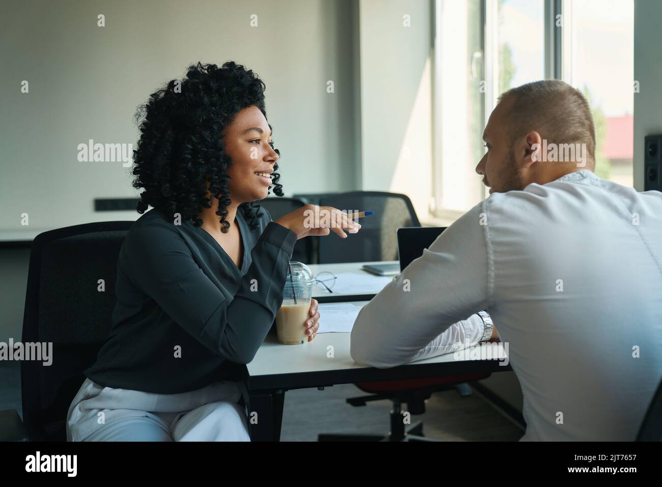 Colleagues communicate in a friendly way at the desktop in the office ...