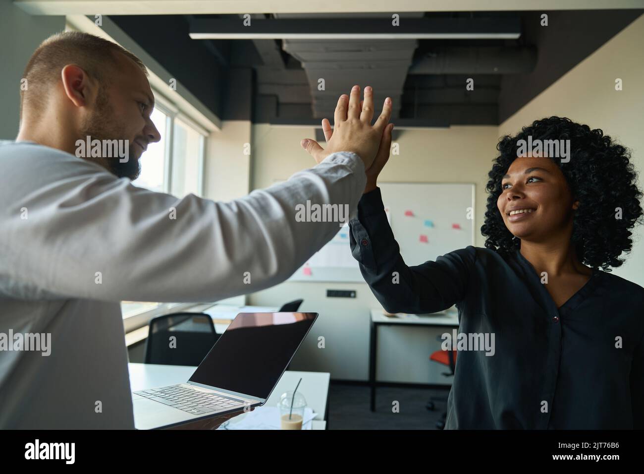 Successful colleagues giving high five for project victory in office ...