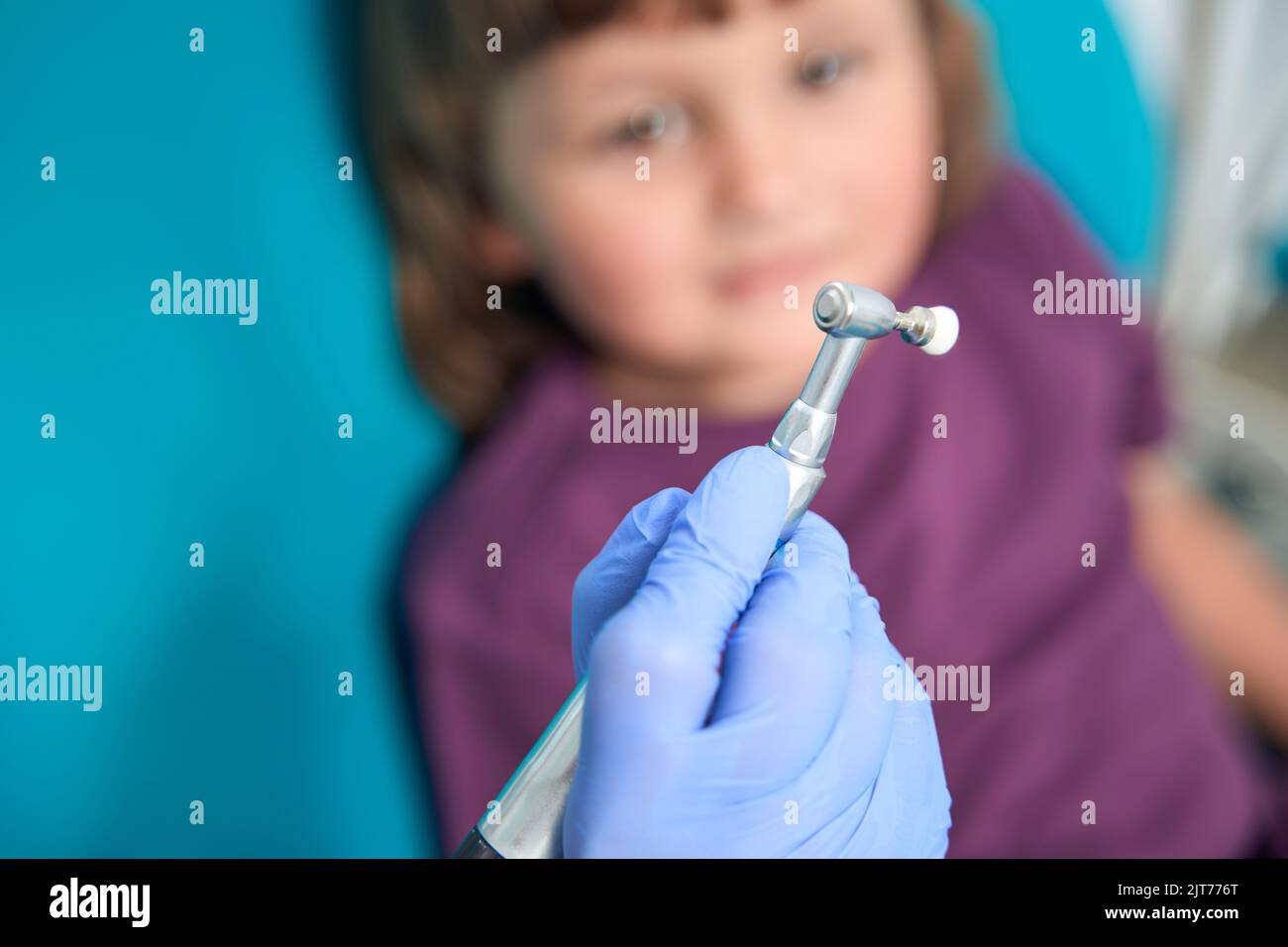 Experienced doctor preparing for polishing of female child tooth enamel ...