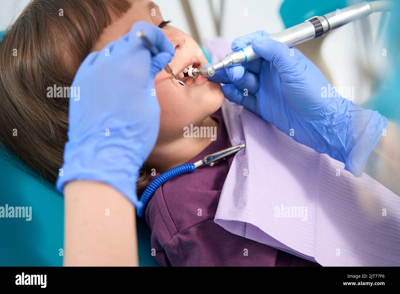 Pediatric dentist conducting teeth-polishing procedure on female child ...