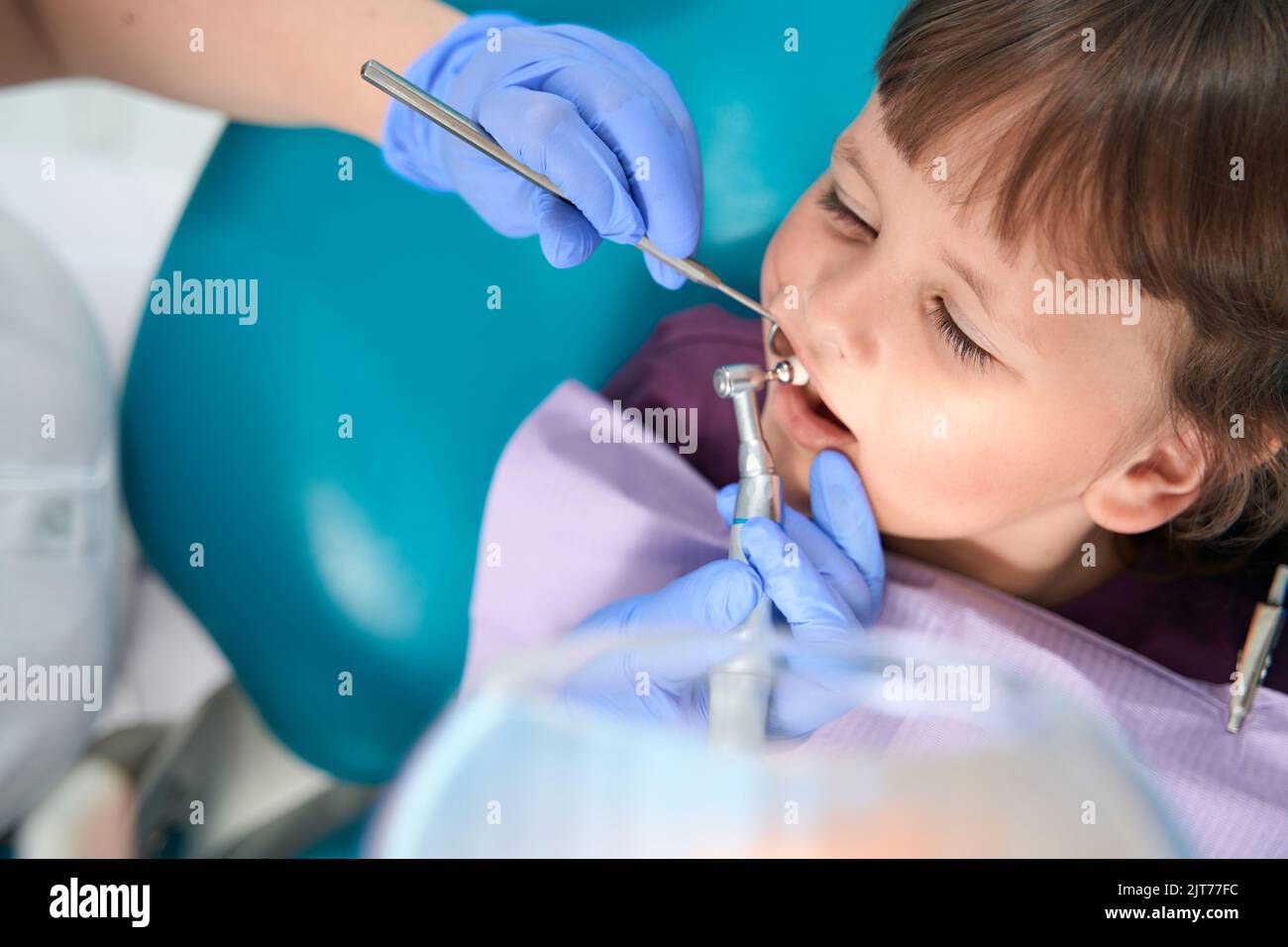 Pediatric dentist carrying out teeth-polishing procedure on female ...