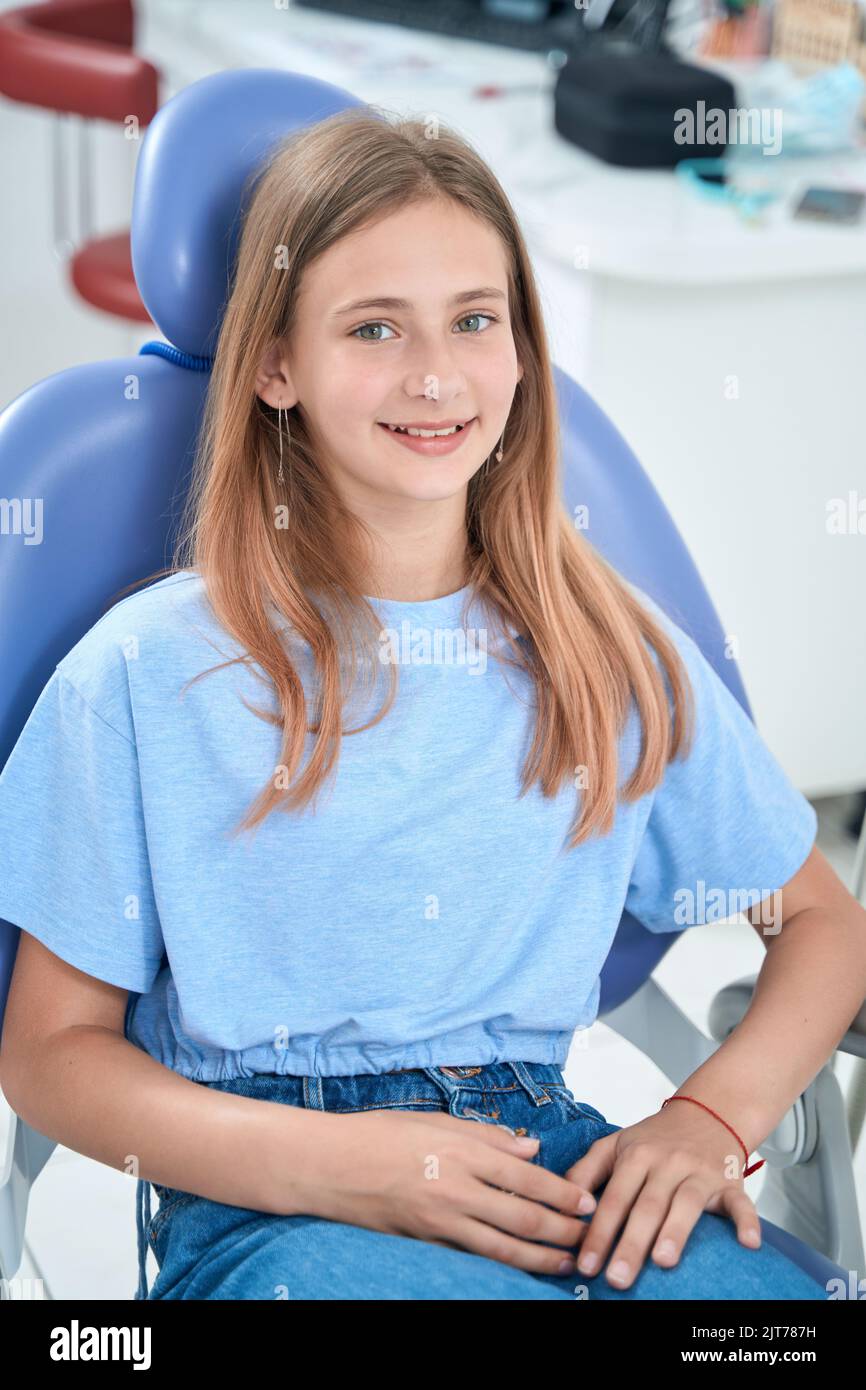 Pleased young lady seated in dental chair Stock Photo - Alamy