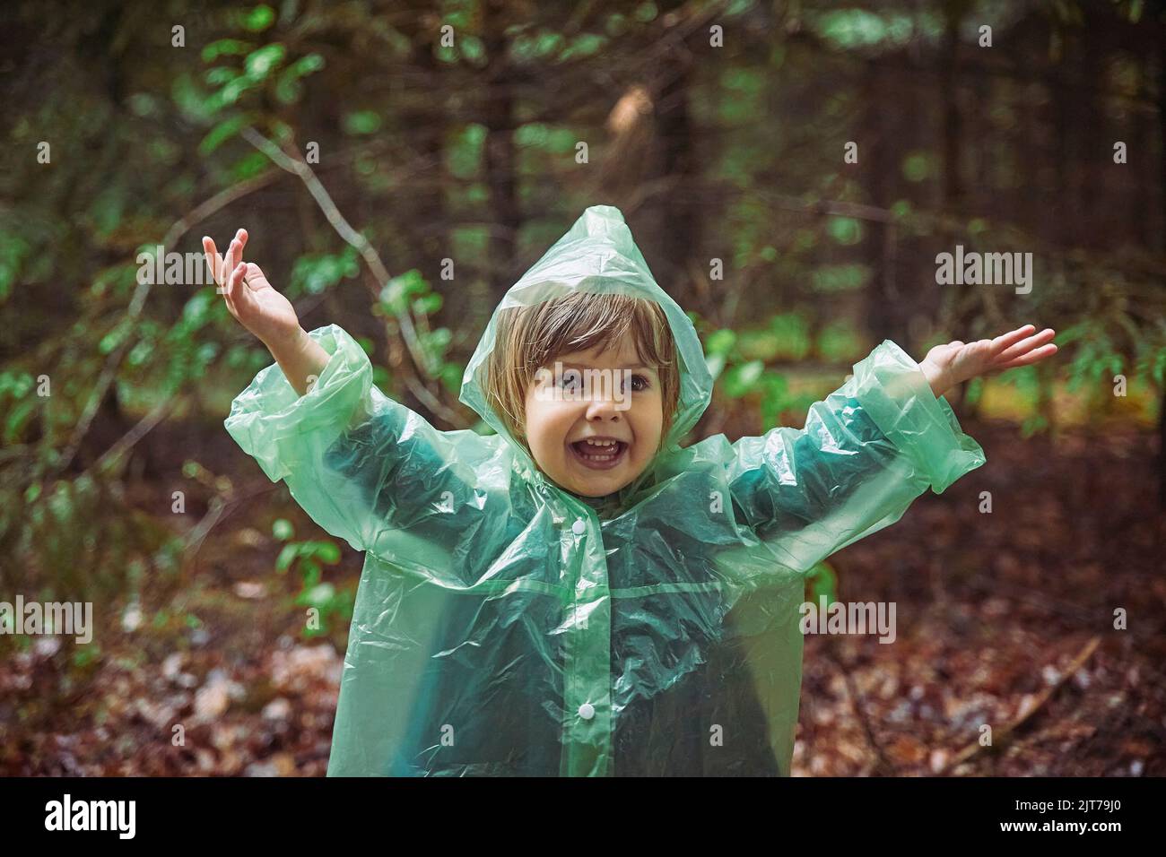 Charming child in raincoat in the evening forest in Denmark Stock Photo ...