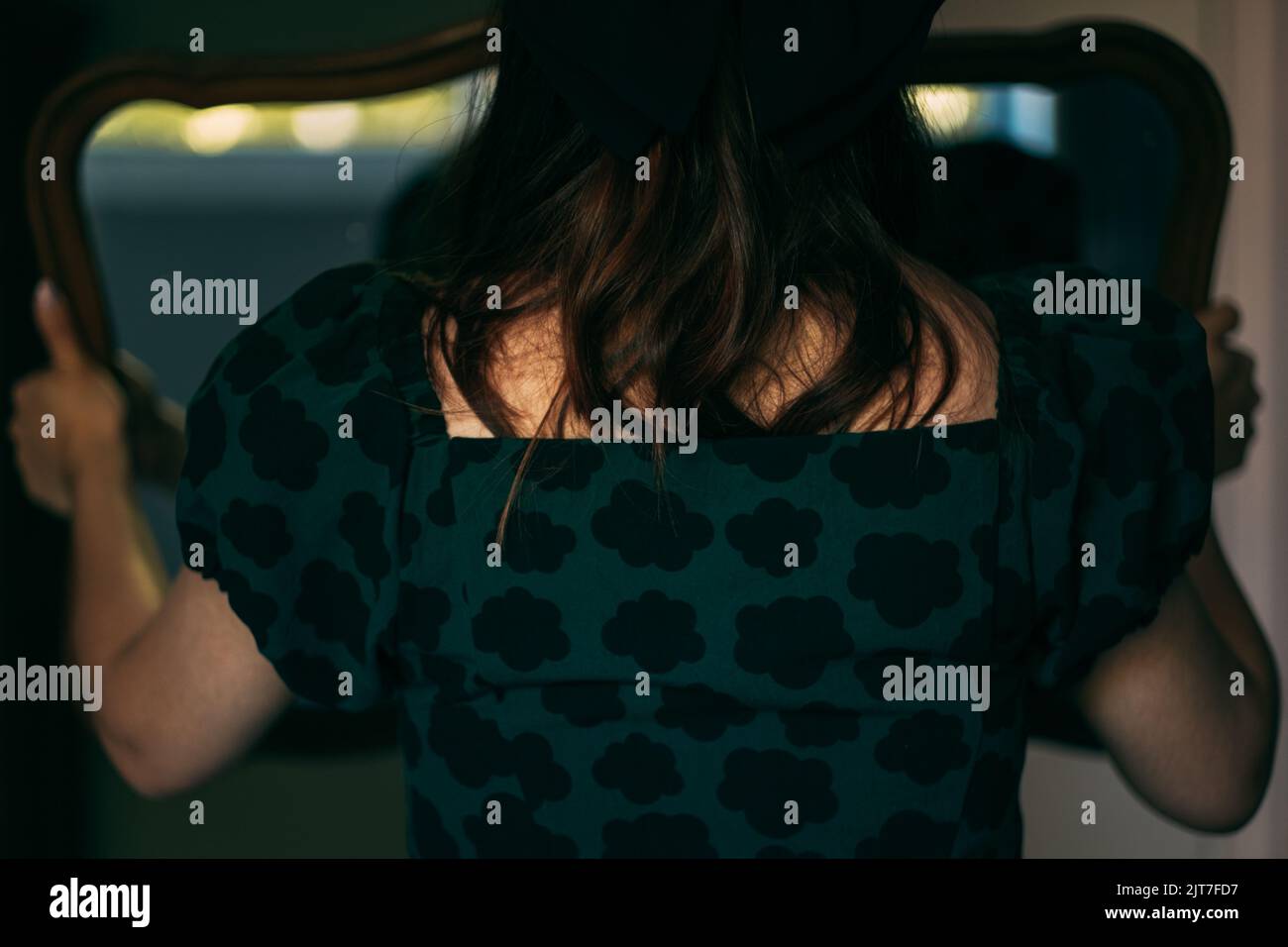 A closeup of a woman from behind holding a mirror Stock Photo - Alamy