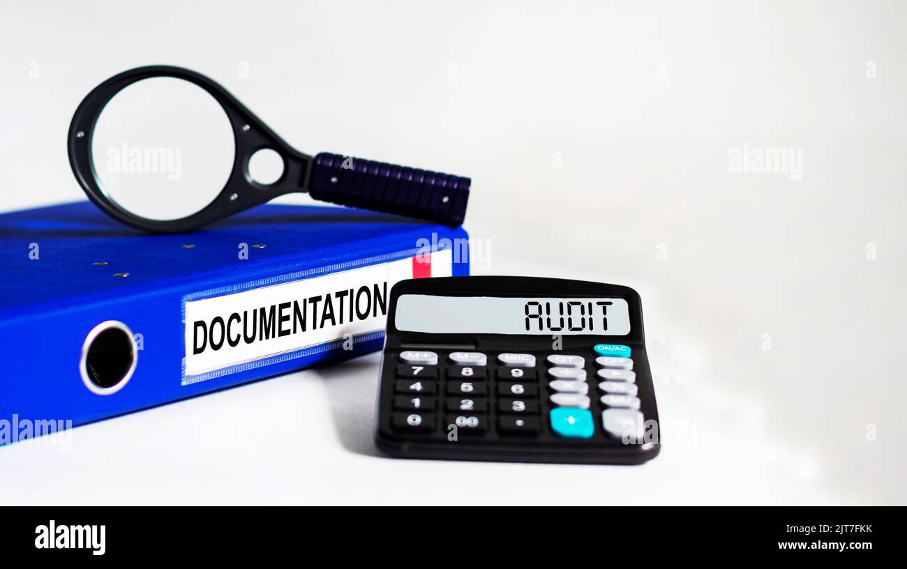 AUDIT text on a calculator on a white background with a blue folder ...