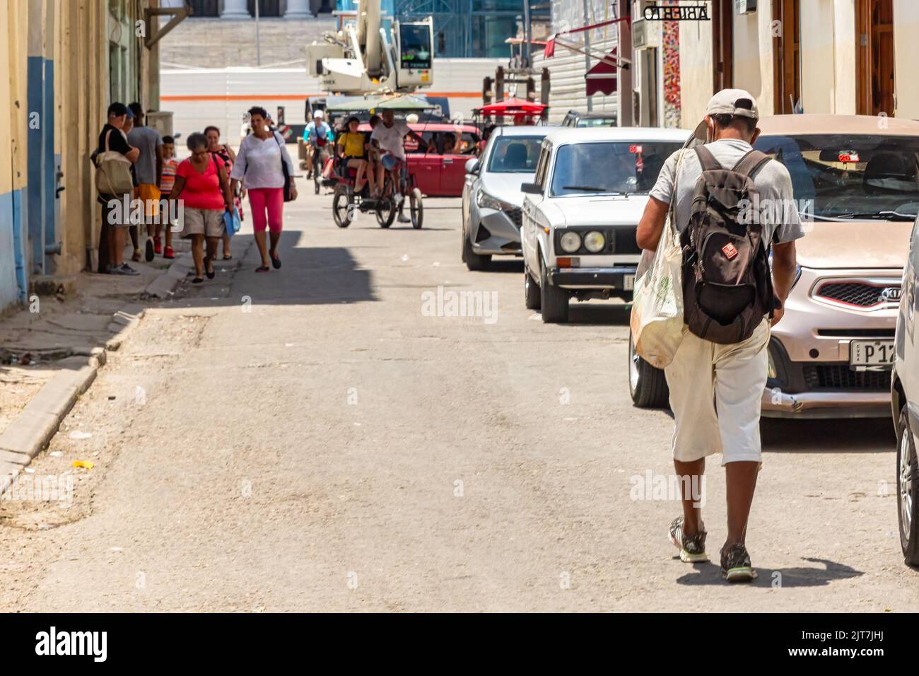 Cuban people walking in a narrow street in the downtown district. There ...