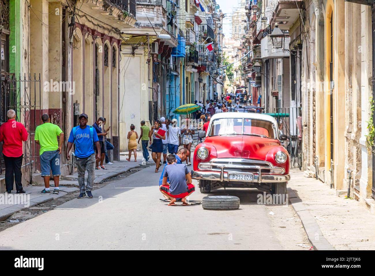 A Cuban driver changes a flat tire of an old American Chevrolet car ...