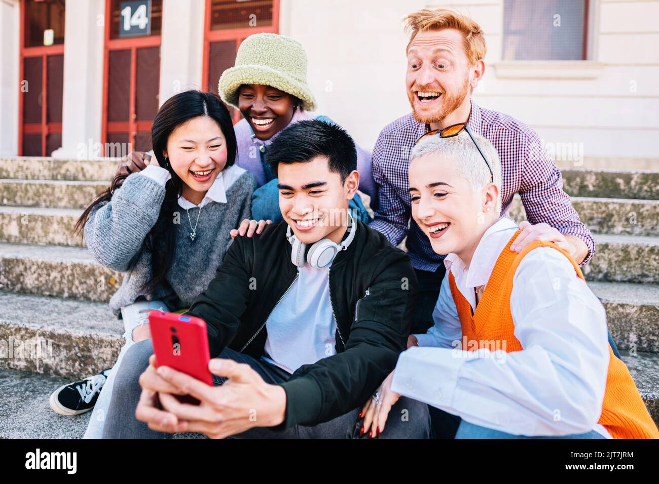 group taking a selfie photo with a smartphone sitting on the floor ...