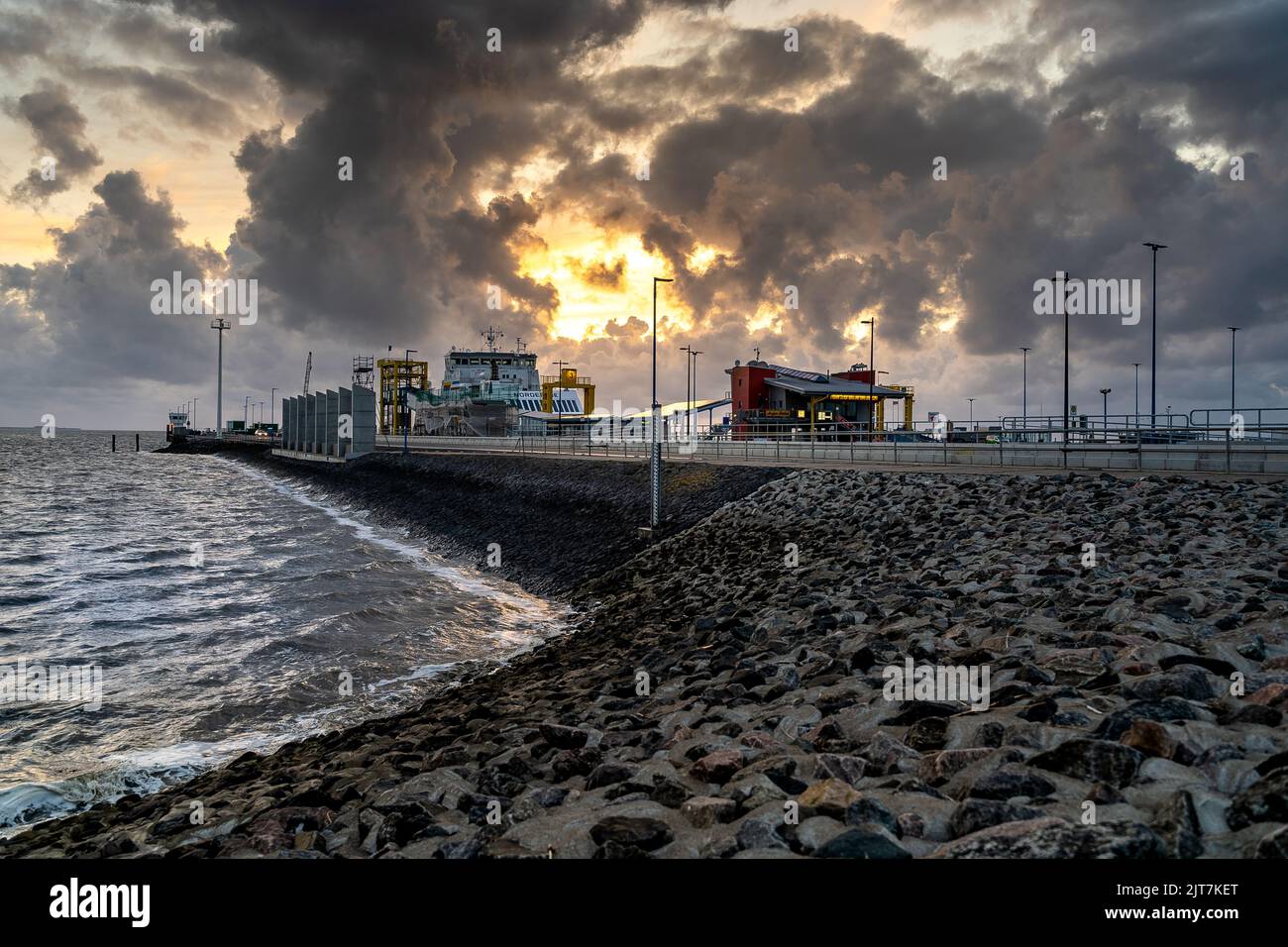 A cloudy sunset on the sandy beach with port and a house near Stock ...