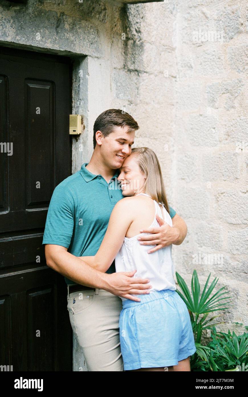 Man hugging a woman near the door of a stone building Stock Photo - Alamy