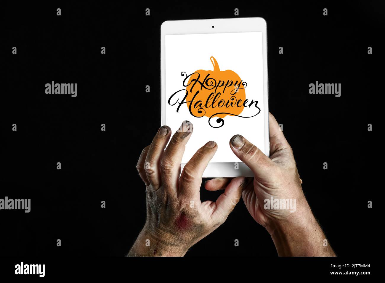 Hands of zombie with tablet computer on dark background. Happy ...