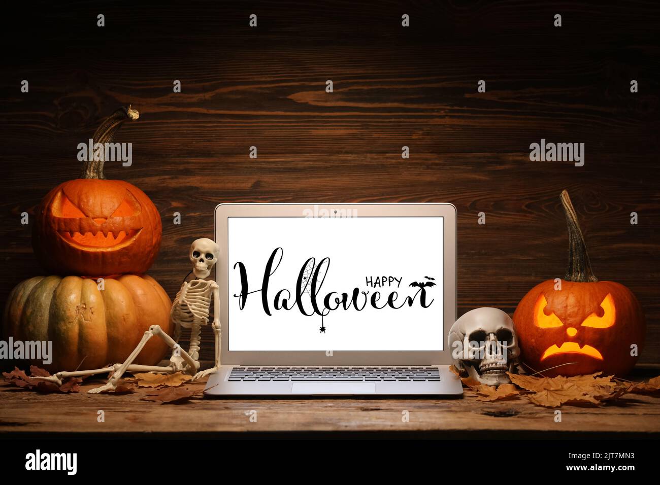 Carved pumpkins, skeleton, skull and laptop with text HAPPY HALLOWEEN ...