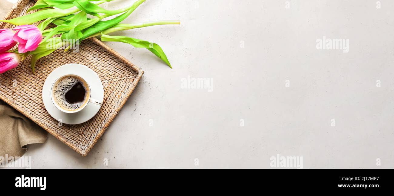 Tray with cup of coffee and flowers on light background with space for ...