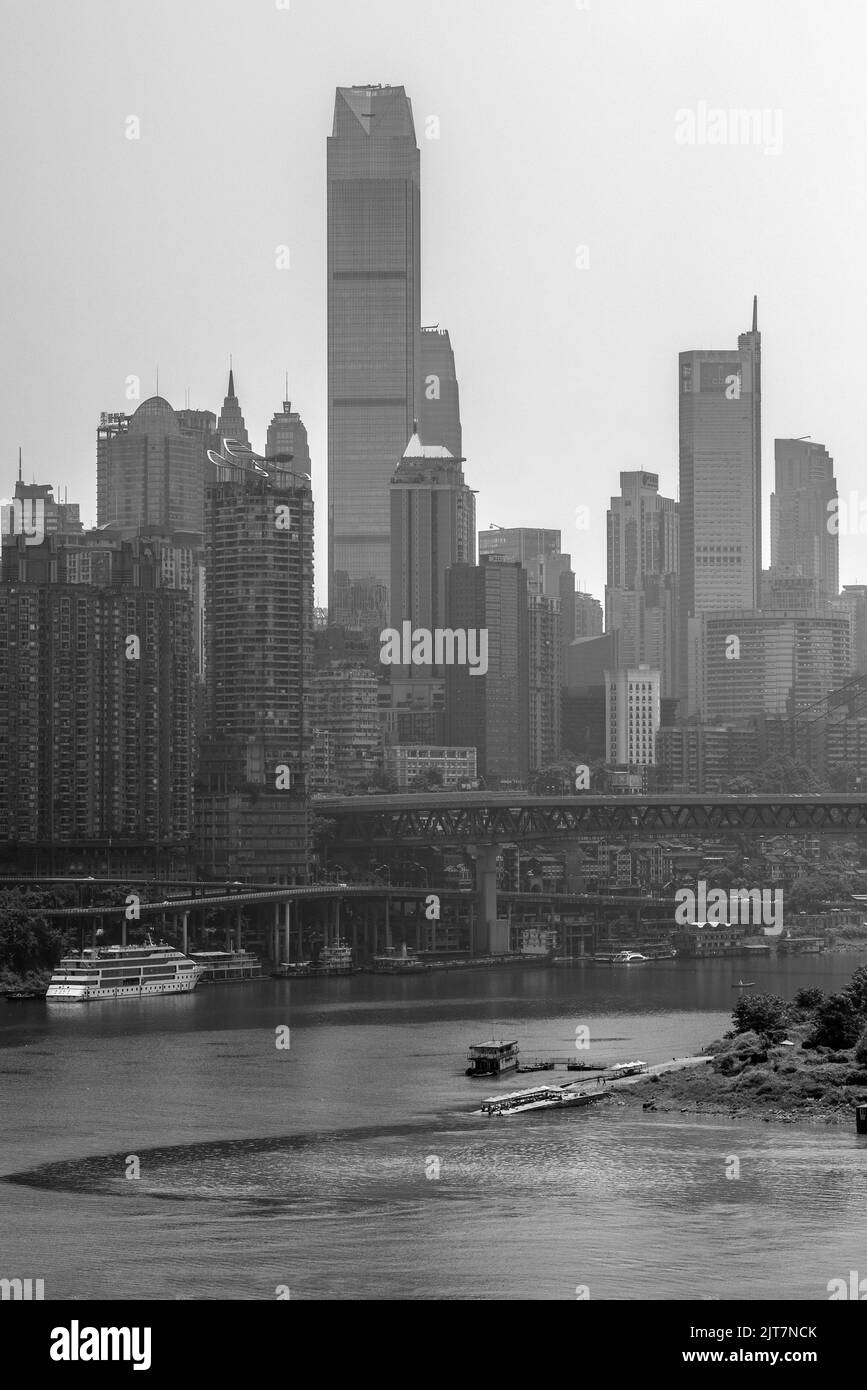 A vertical shot of a boat sailing in the river with buildings in the ...