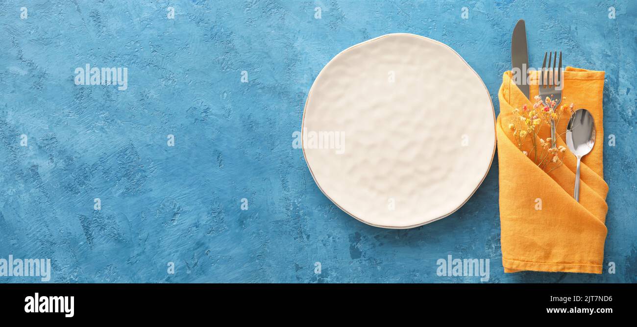 Simple table setting with floral decor on blue background with space ...