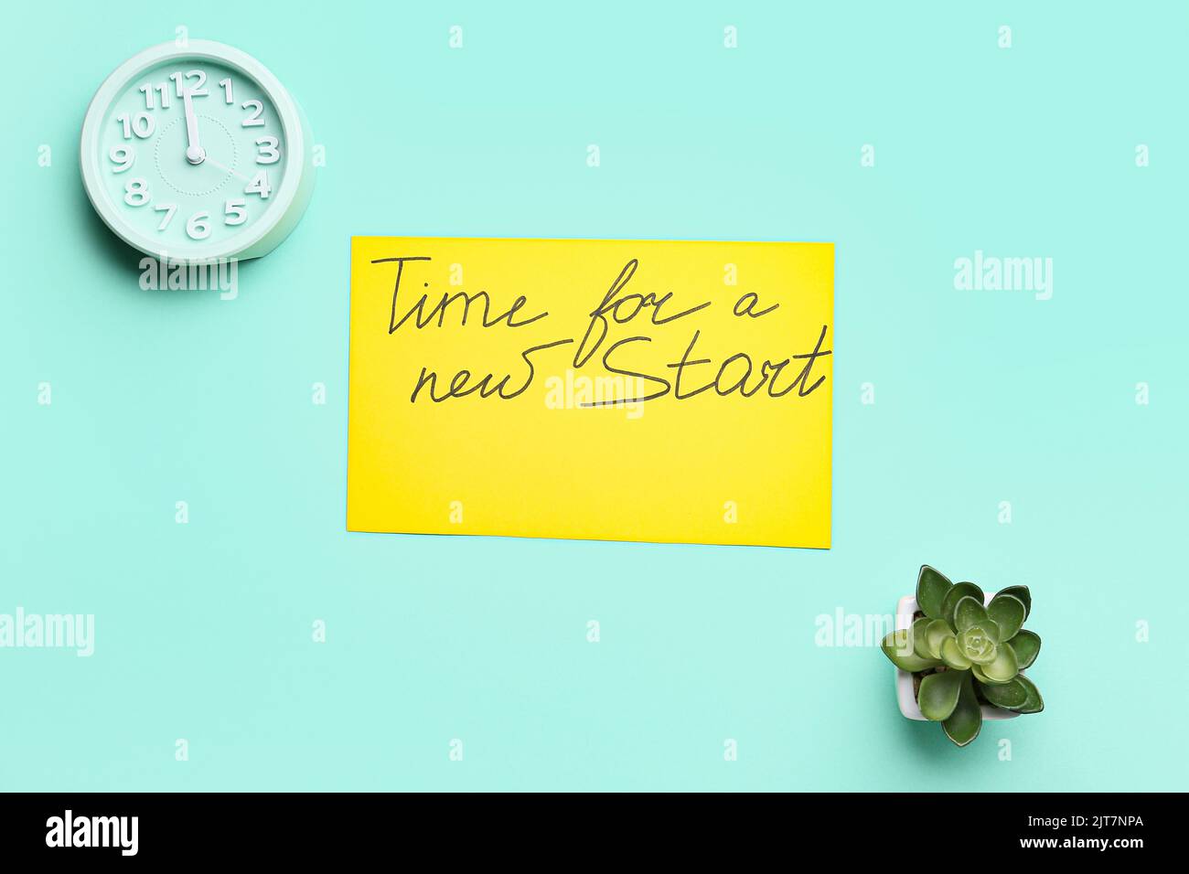 Paper sheet with text TIME FOR A NEW START, alarm clock and plant on ...