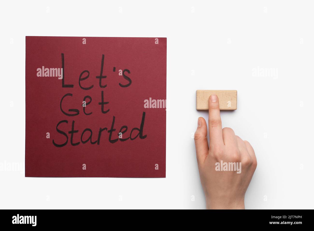 Paper sheet with text LET'S GET STARTED and female hand with wooden ...