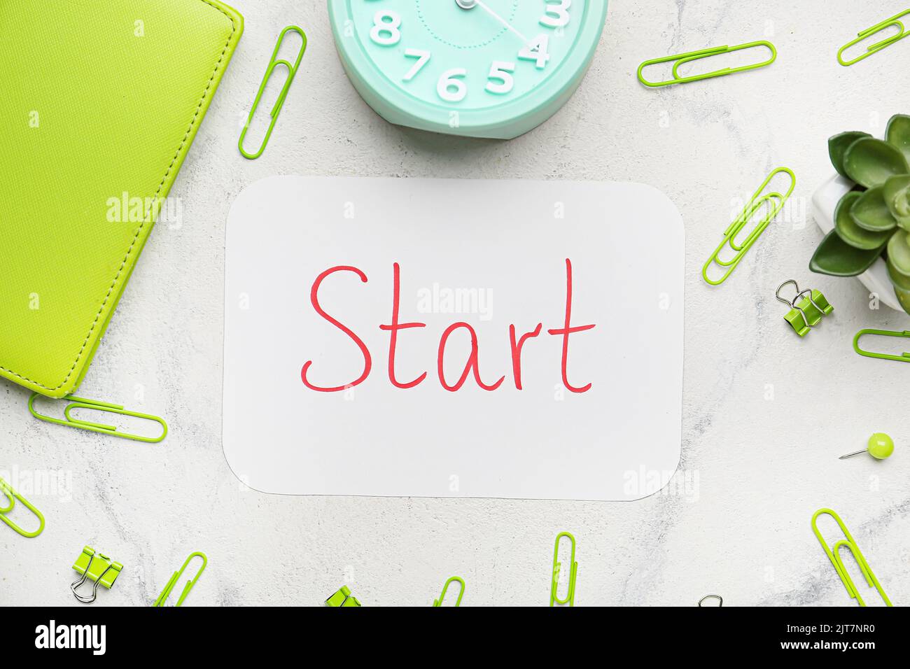 Paper sheet with word START, alarm clock and stationery on white ...