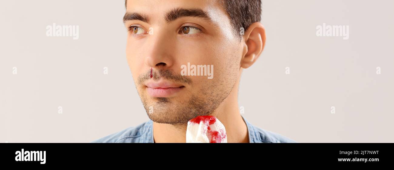 Young man having nosebleed on light background Stock Photo - Alamy