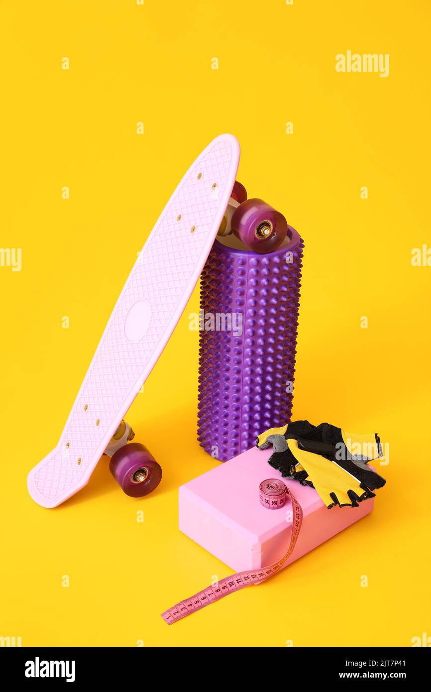 Foam roller with skateboard, block, gloves and measuring tape on yellow ...