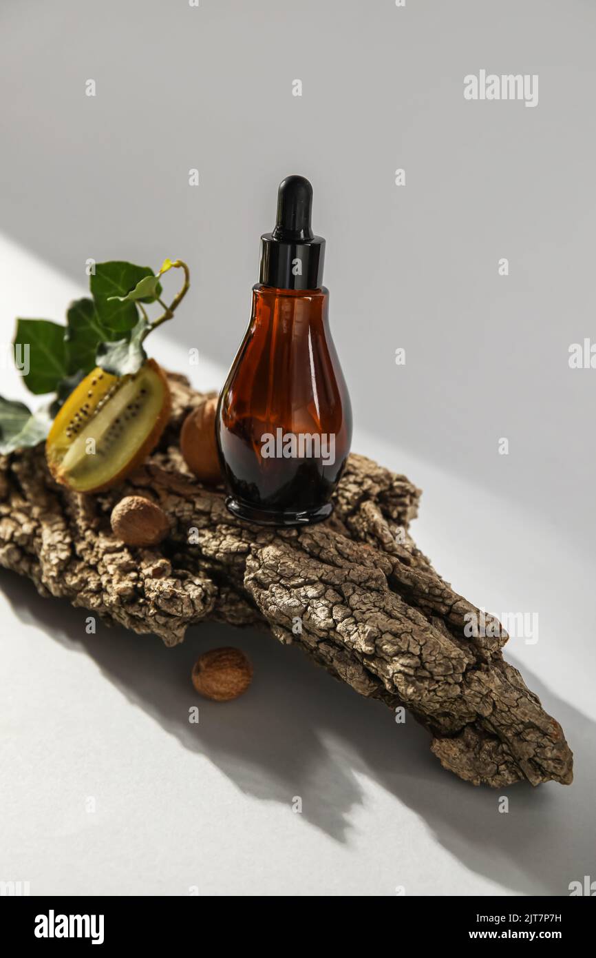 Composition with bottle of essential oil, nuts, kiwi and tree bark on ...