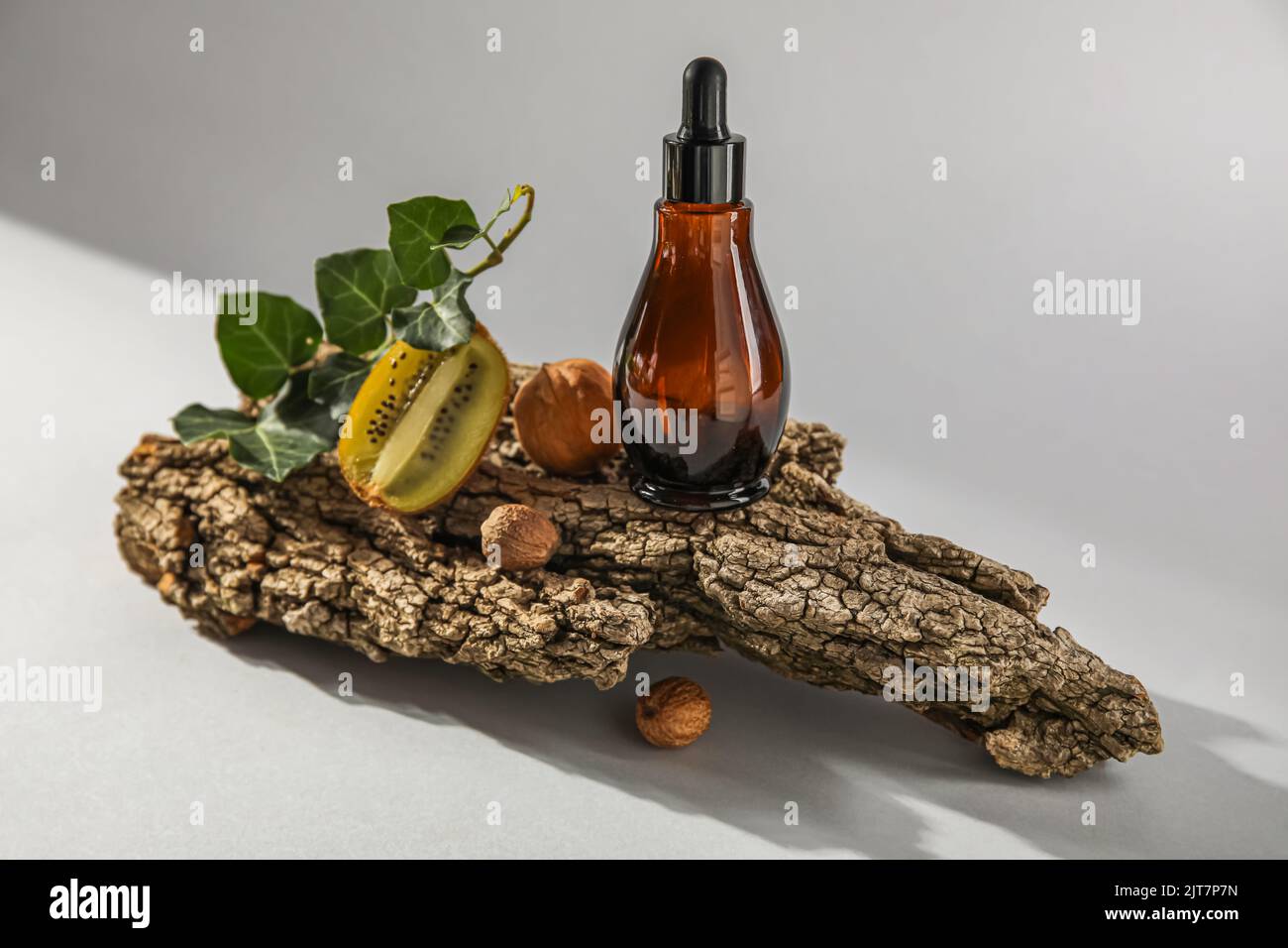 Composition with bottle of essential oil, nuts, kiwi and tree bark on ...