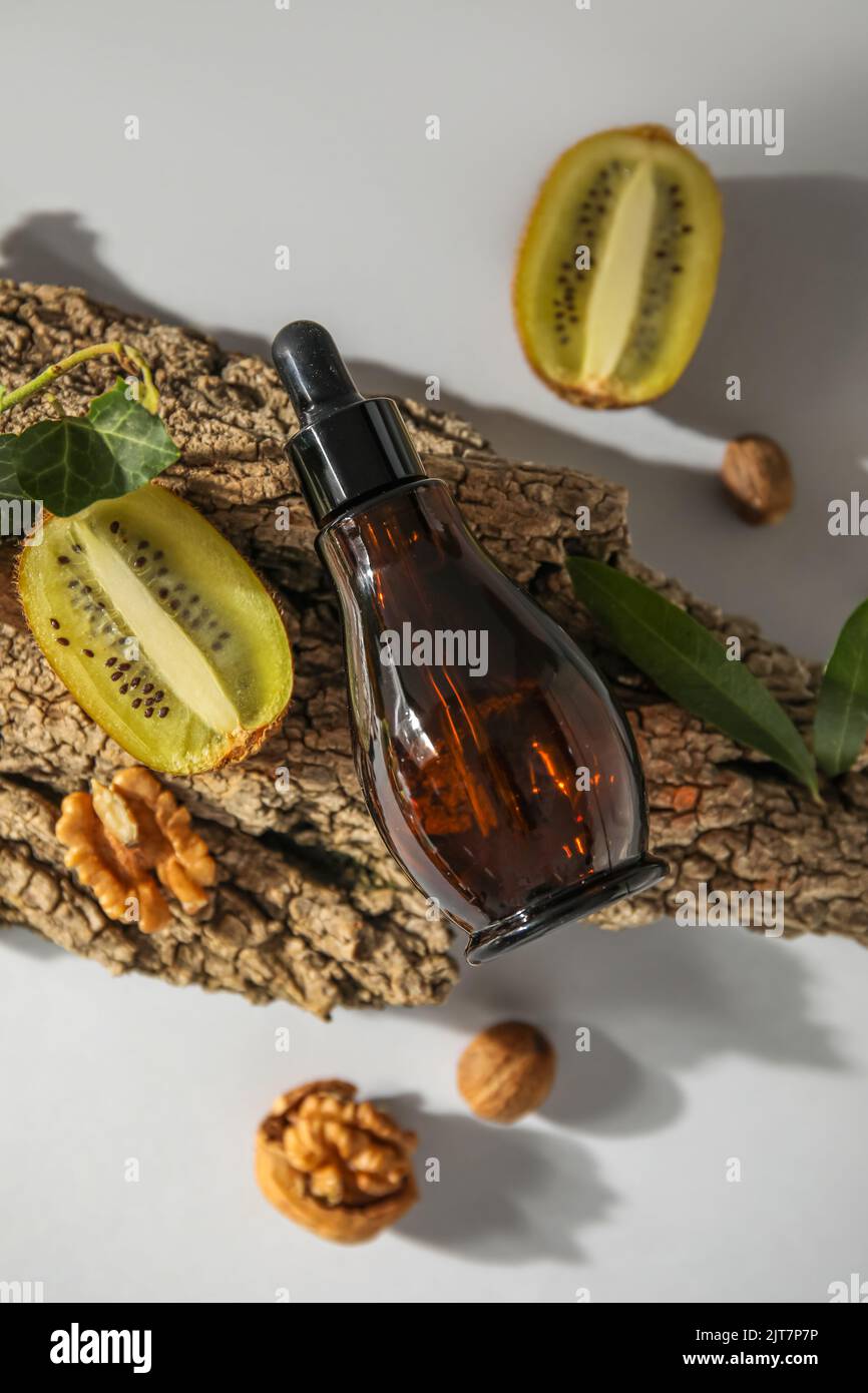 Composition with bottle of essential oil, kiwi, walnuts and tree bark ...