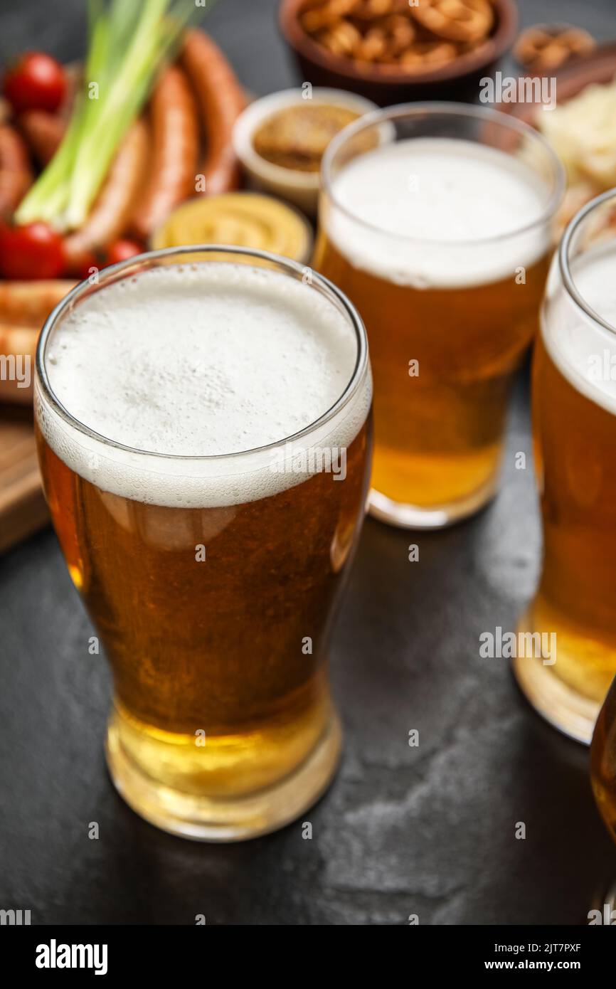 Mugs of fresh beer and traditional food on dark background, closeup ...
