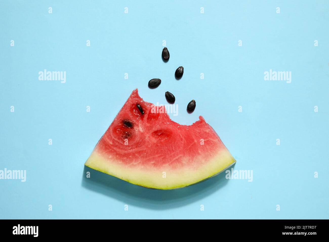 Slice of bitten watermelon with seeds on blue background Stock Photo ...