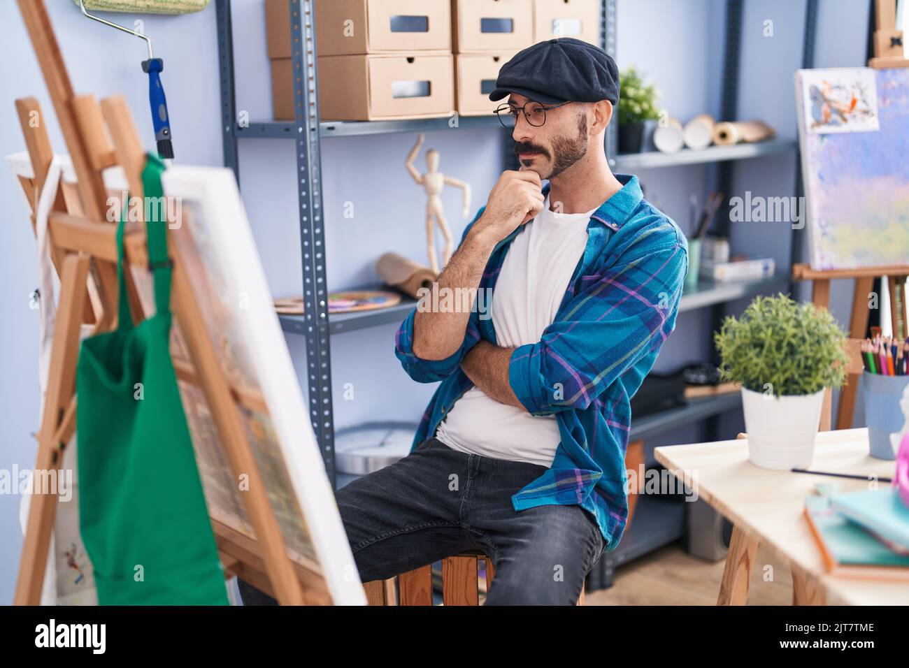 Young hispanic man artist looking draw with doubt expression at art ...