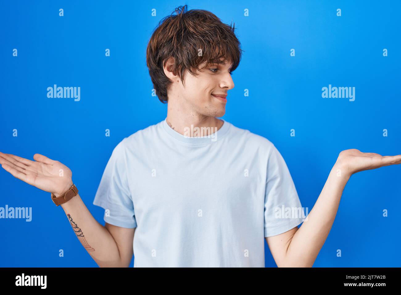 Hispanic young man standing over blue background smiling showing both ...