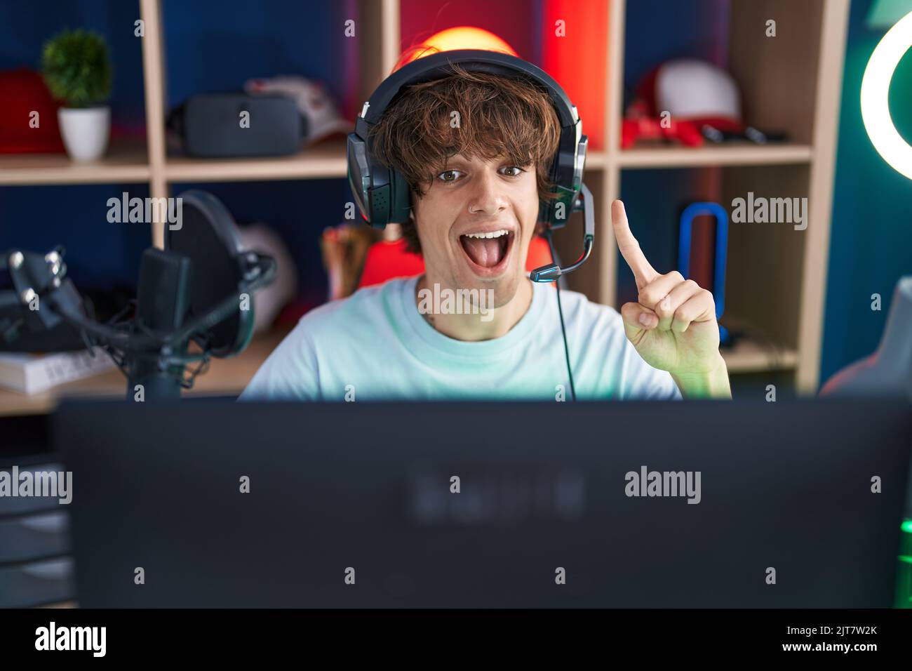 Hispanic young man playing video games smiling with an idea or question ...