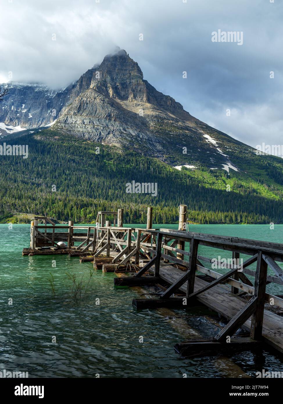 Lake in Glacier National Park with a Dock and clouds above mountain ...