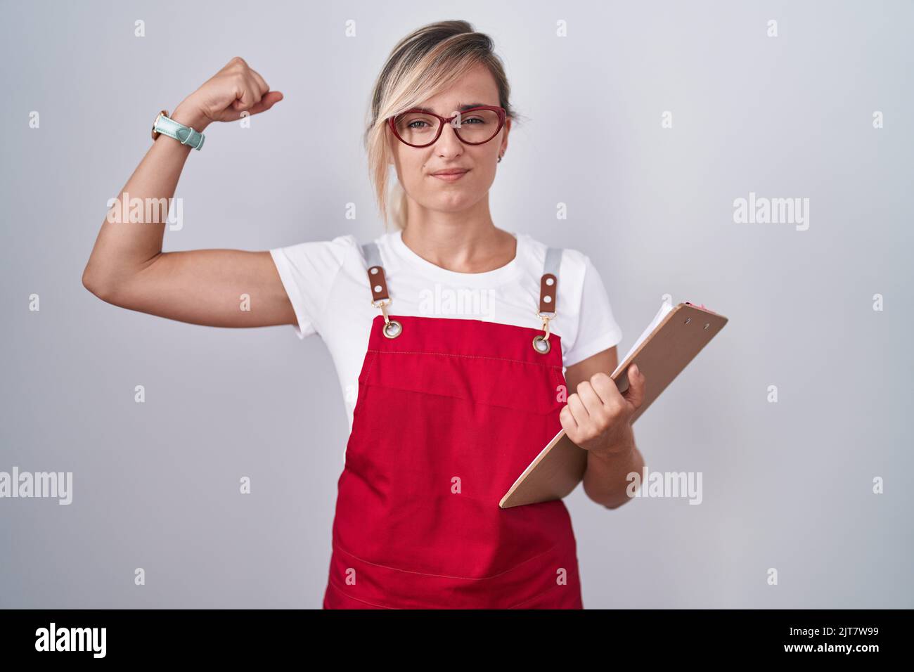 Young blonde woman wearing waiter uniform holding clipboard strong ...
