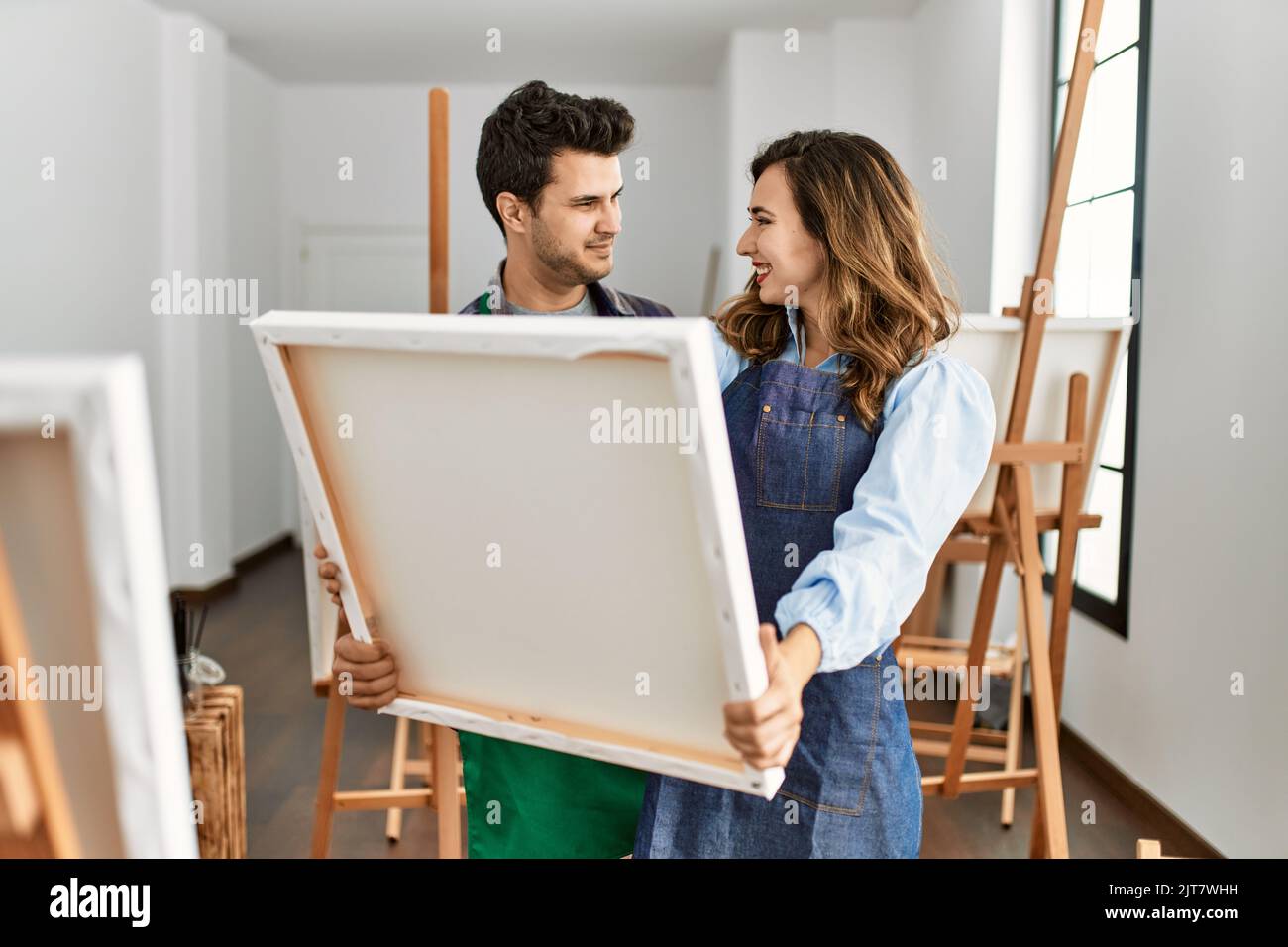 Two hispanic students smiling happy holding canvas at art school Stock ...