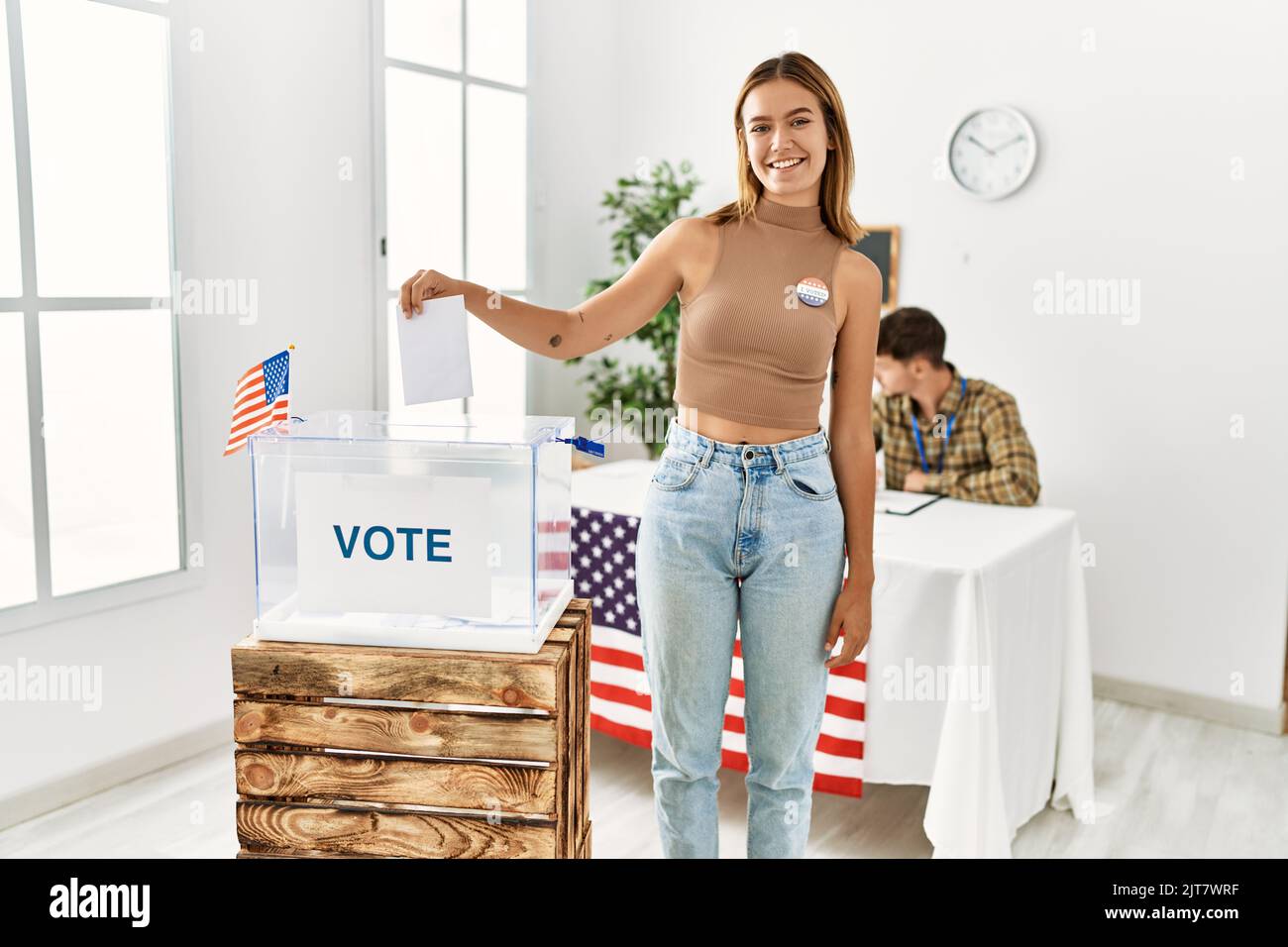 Young blonde girl voting putting envelop in ballot box looking positive ...
