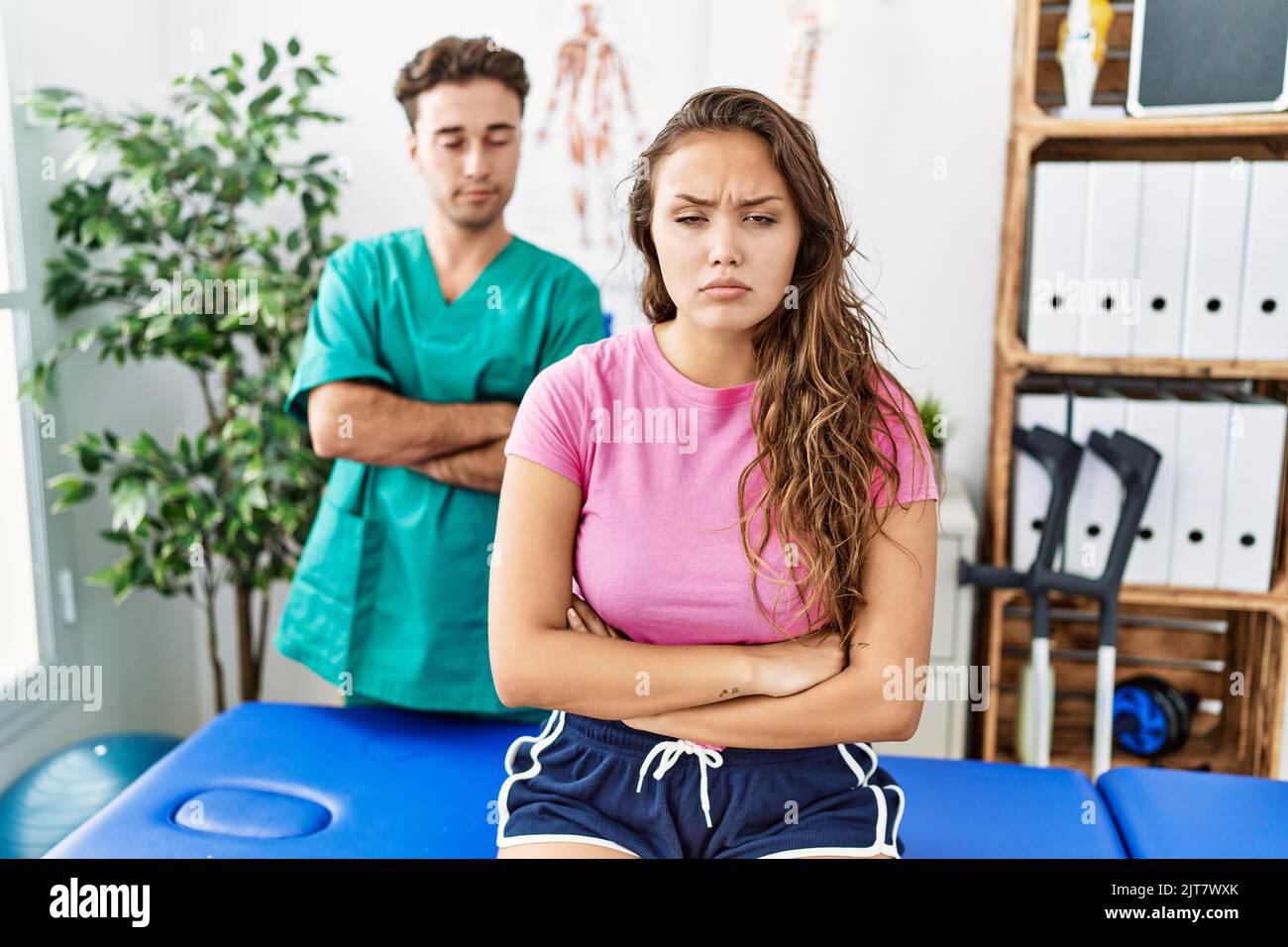Young hispanic woman at physiotherapist appointment skeptic and nervous ...