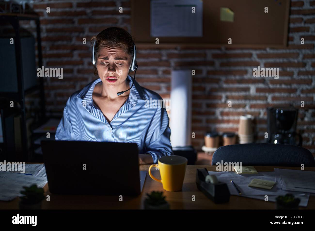 Beautiful brunette woman working at the office at night depressed and ...